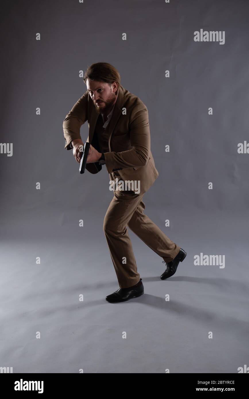 Isolated image of an undercover cop with a gun against a plain ...