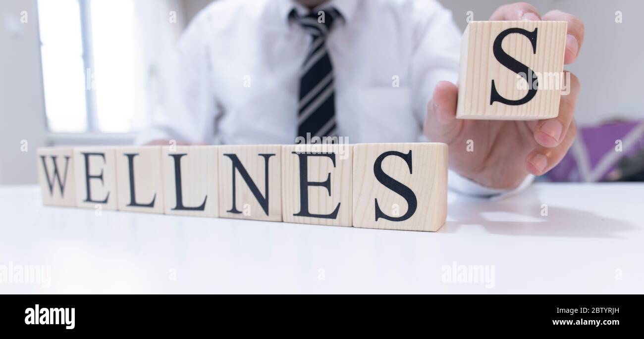 The word wellness from wooden cubes. Man in shirt and tie on the ...