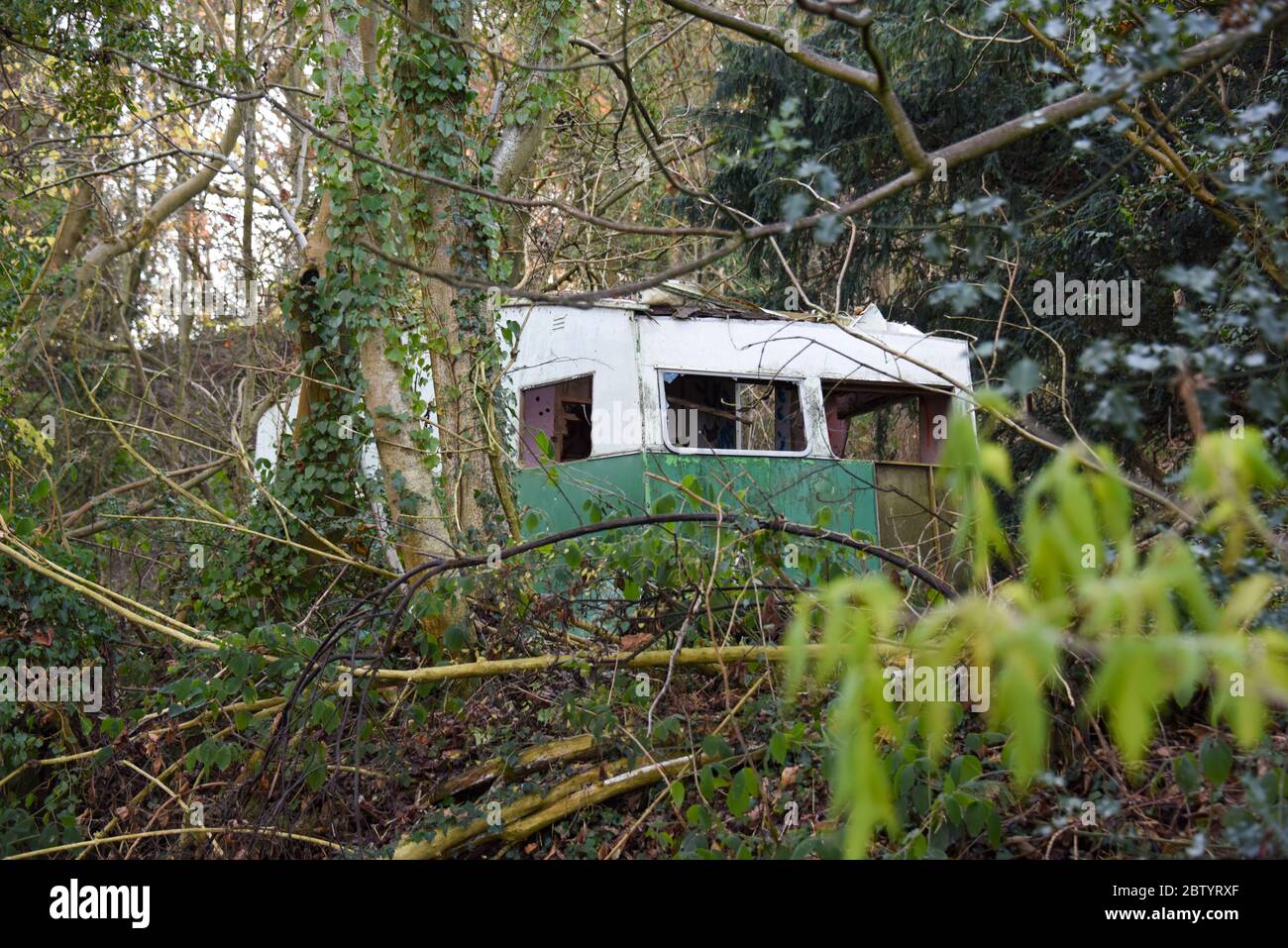 Old green and white dilapidated caravan with windows missing and badly ...