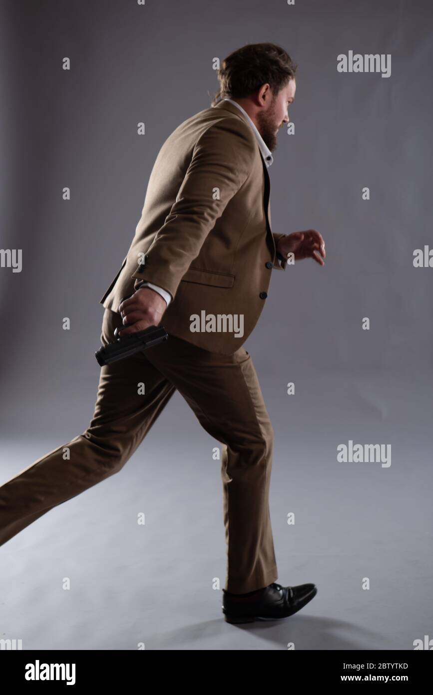 Isolated image of an undercover cop with a gun against a plain ...