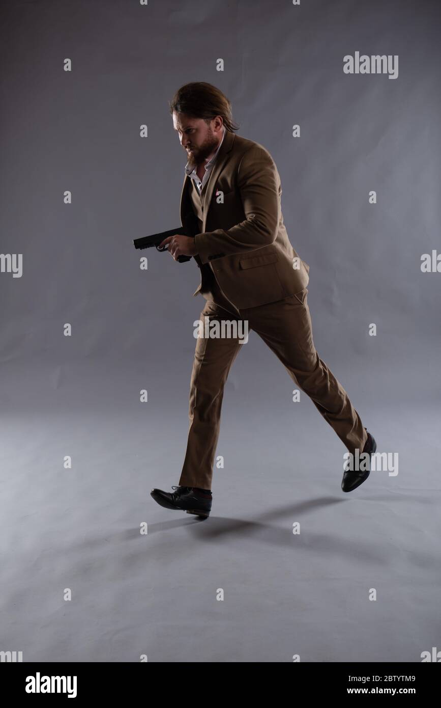 Isolated image of an undercover cop with a gun against a plain ...