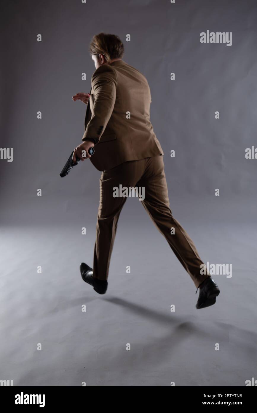 Isolated image of an undercover cop with a gun against a plain ...