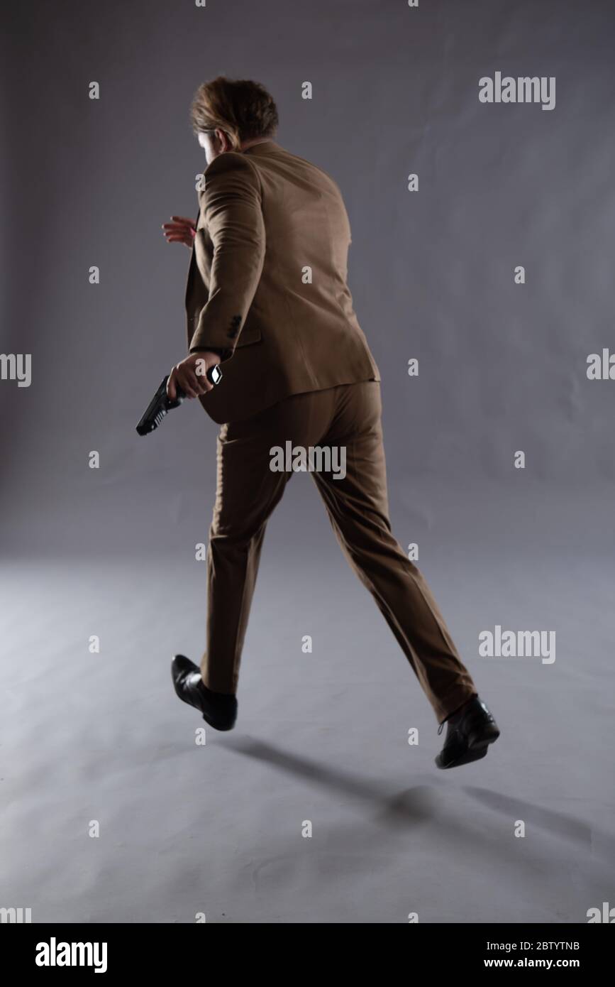 Isolated image of an undercover cop with a gun against a plain ...