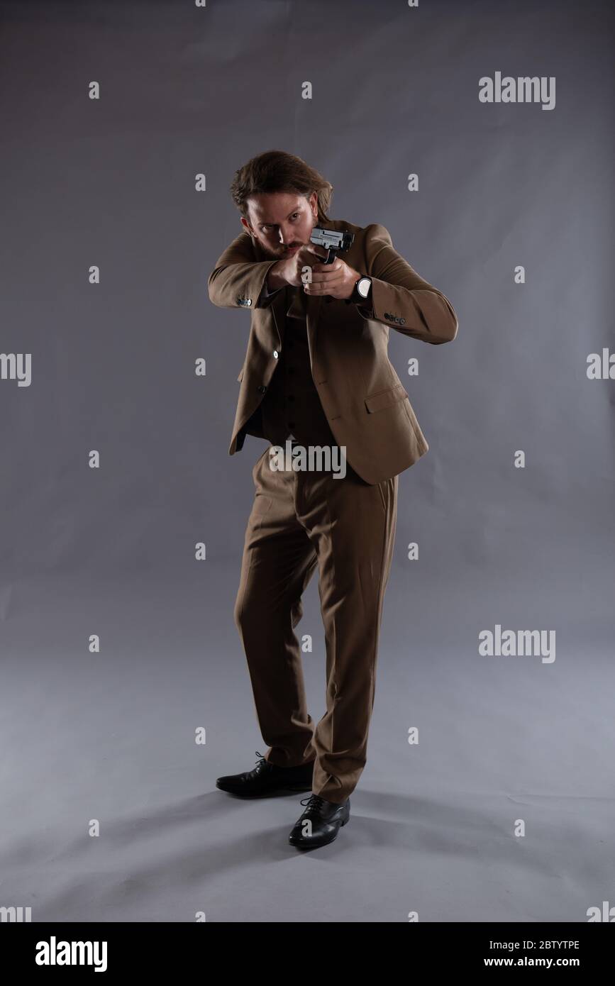 Isolated image of an undercover cop with a gun against a plain ...