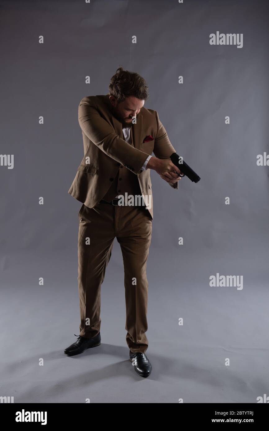 Isolated image of an undercover cop with a gun against a plain ...
