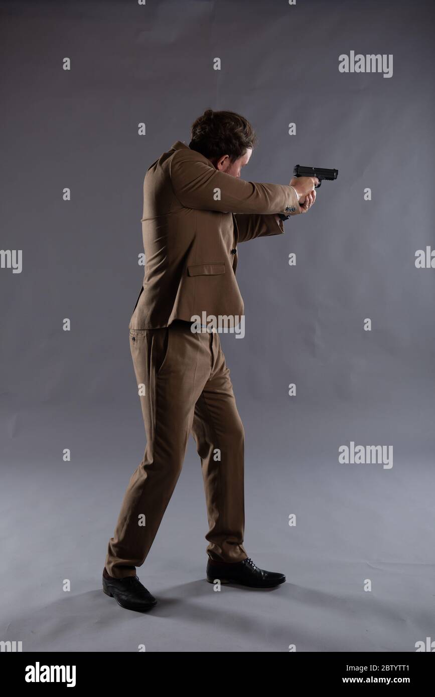 Isolated image of an undercover cop with a gun against a plain ...