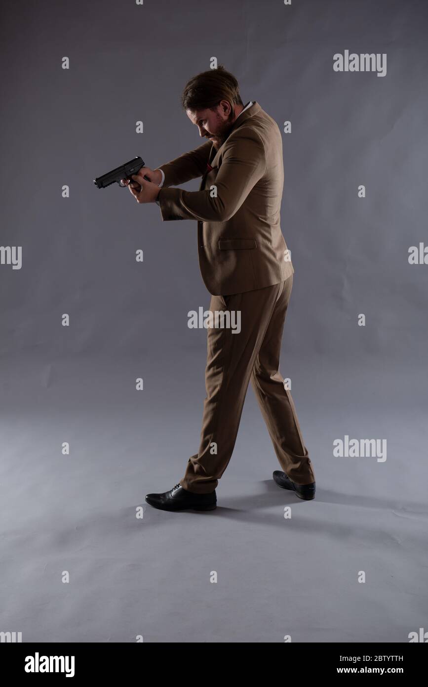 Isolated image of an undercover cop with a gun against a plain ...