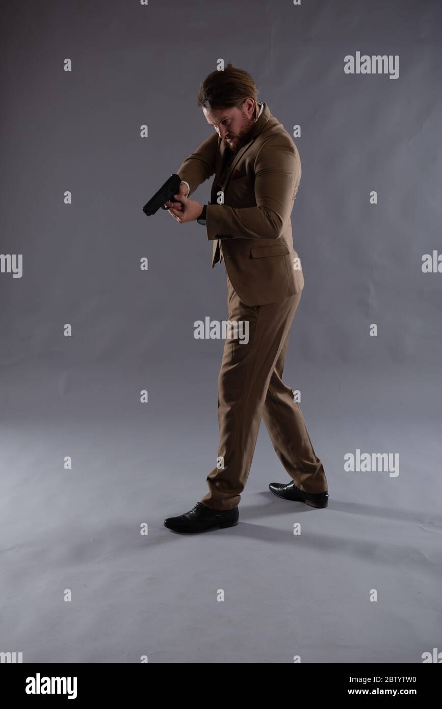 Isolated image of an undercover cop with a gun against a plain ...
