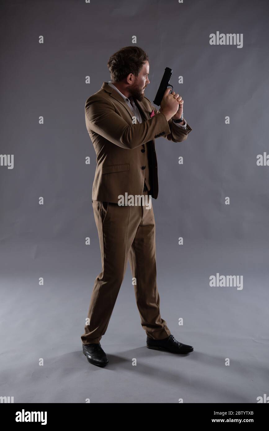 Isolated image of an undercover cop with a gun against a plain ...