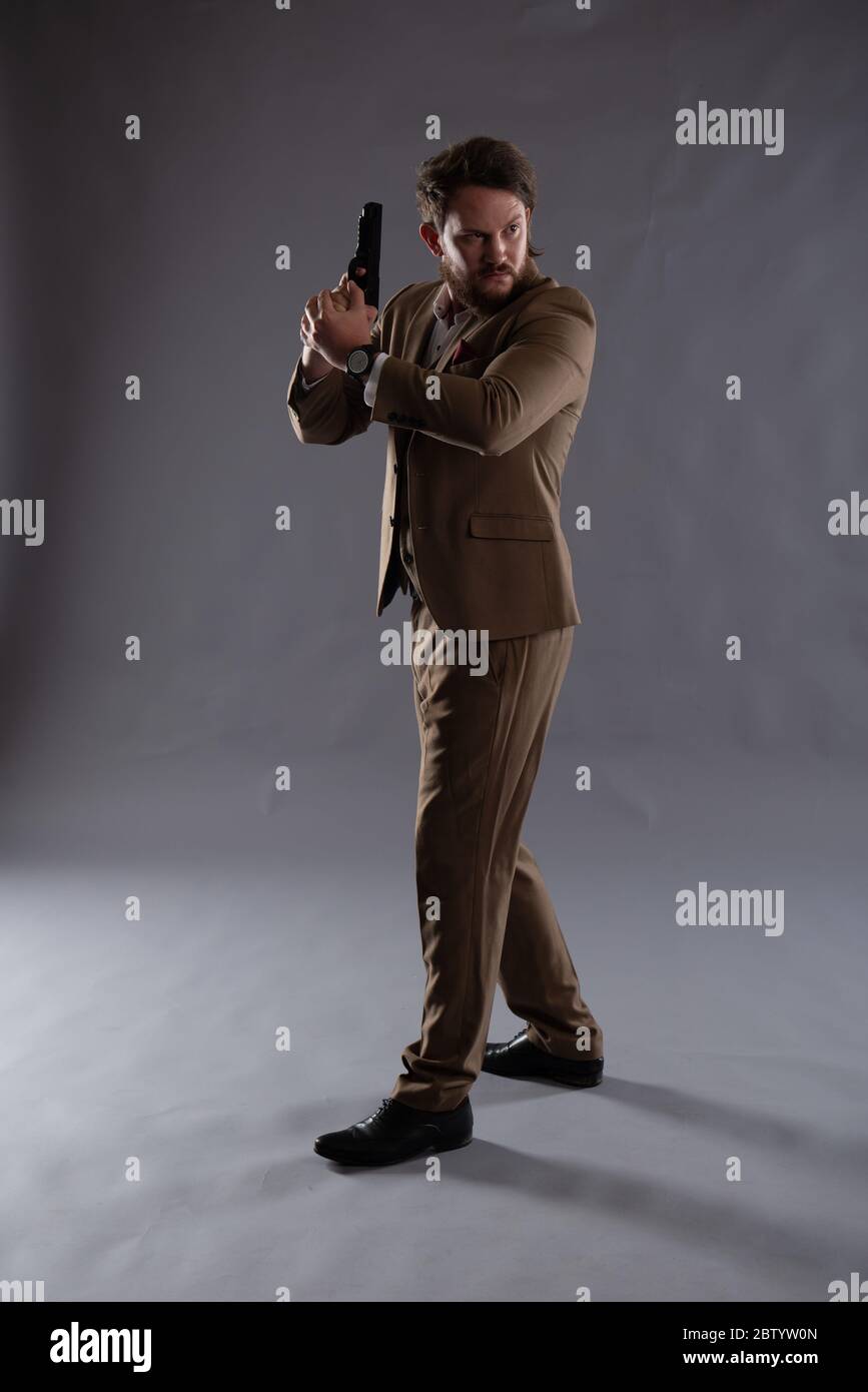 Isolated image of an undercover cop with a gun against a plain ...