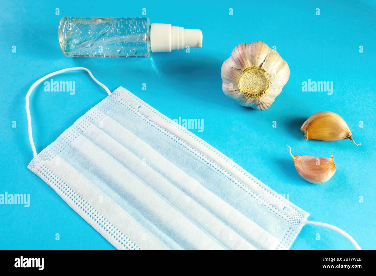Medical mask, garlic and alcohol gel on blue background. Concept of ...