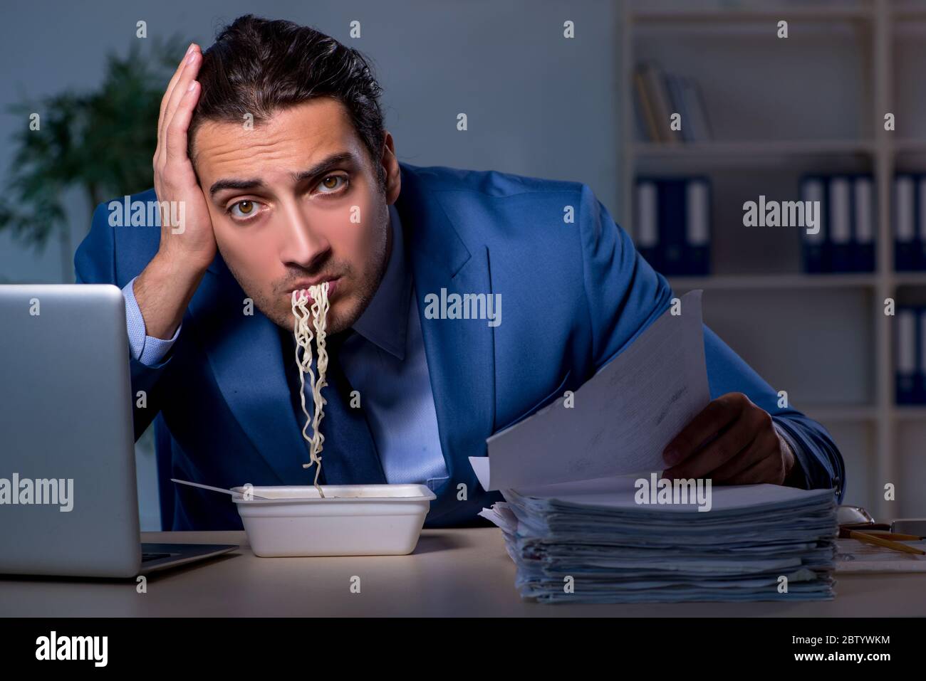 Hungry employee working late in office Stock Photo - Alamy