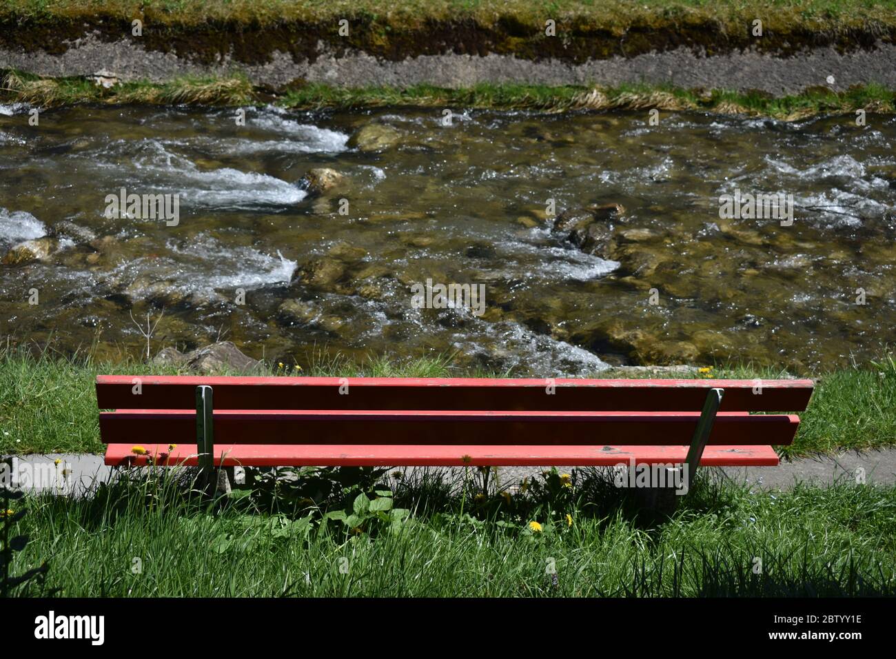 Red empty bench next to a river Stock Photo - Alamy