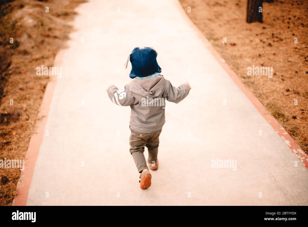 Rear view of baby boy running on footpath in park Stock Photo - Alamy