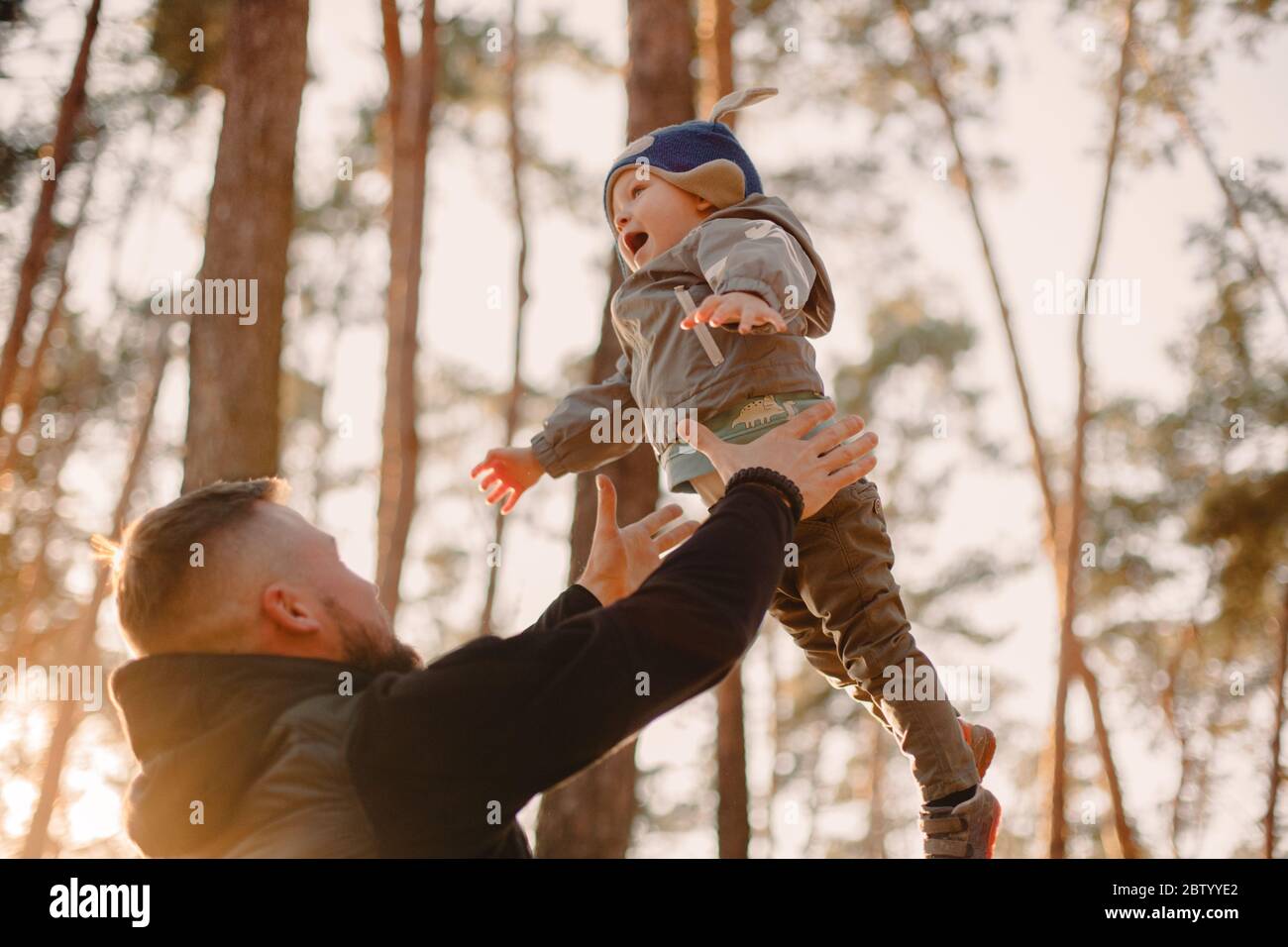 Father throwing son in air while playing in forest Stock Photo - Alamy