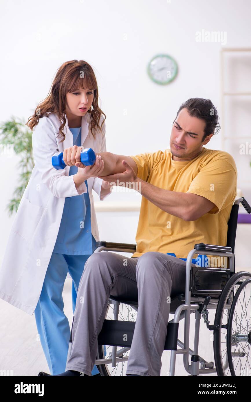 Young male patient in wheel-chair doing physical exercises in hospital ...