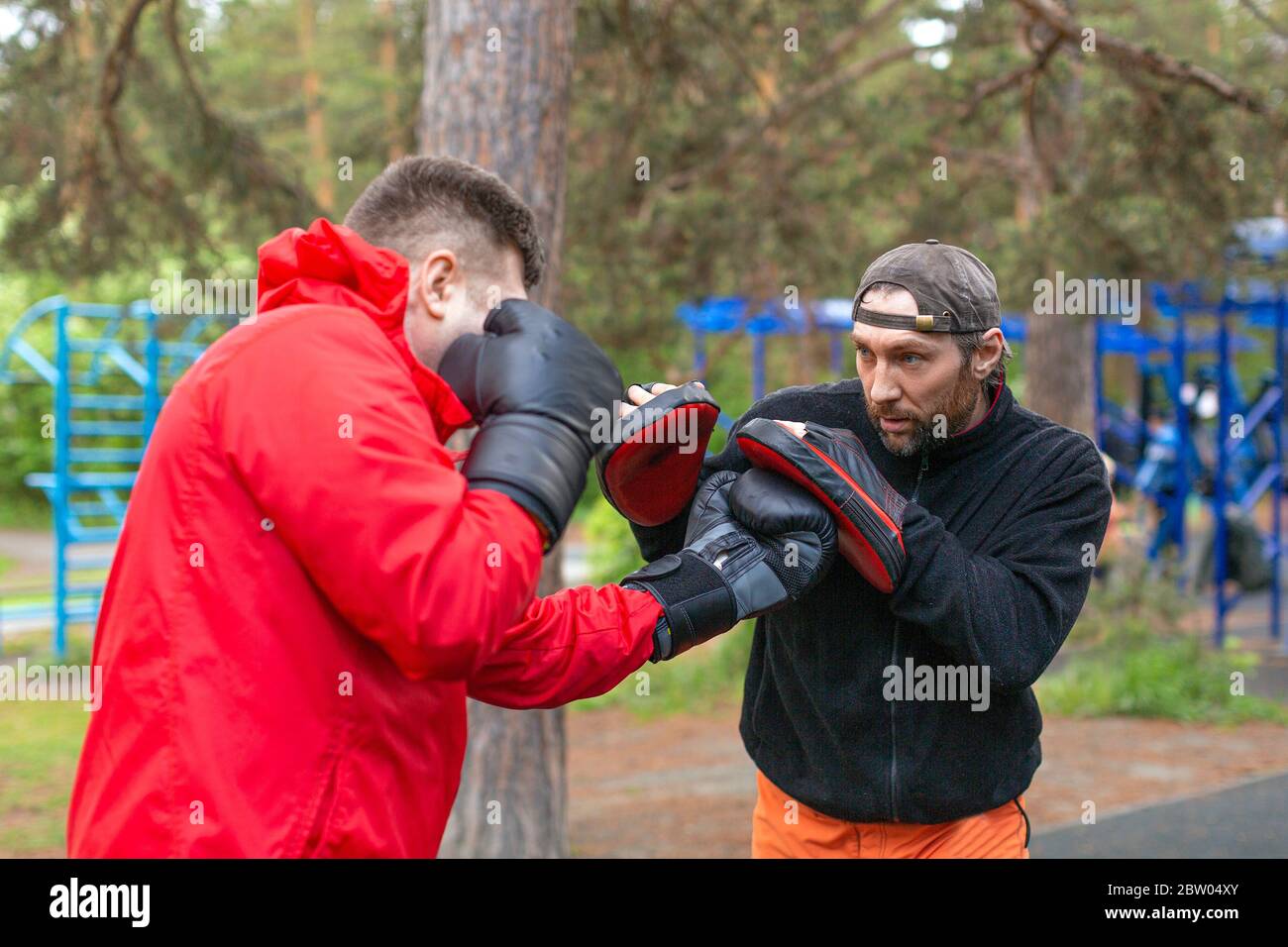 Middle-aged boxer training with coach outdoors. Active and healthy ...