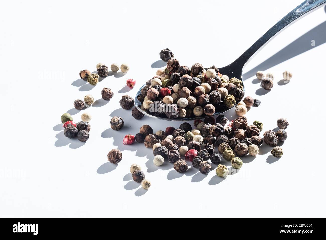 pepper mix in a metal spoon. isolated on white Stock Photo - Alamy