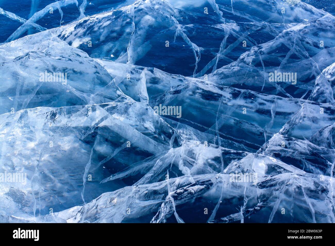 Natural texture of transparent clear ice with bright white cracks. A ...