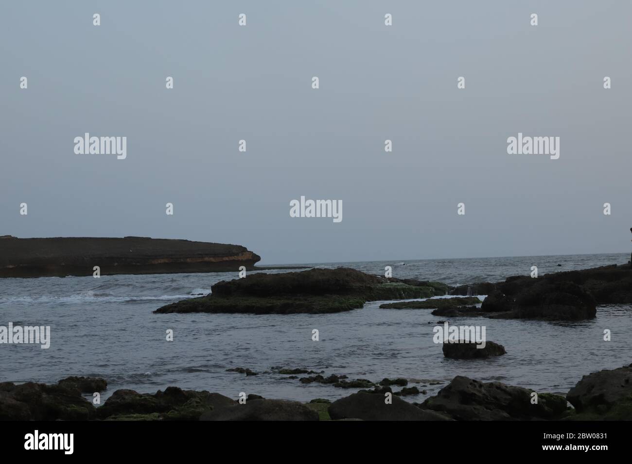 See. Beach with rocks and a cloudy sky. See Waves Touching Rocks Stock ...