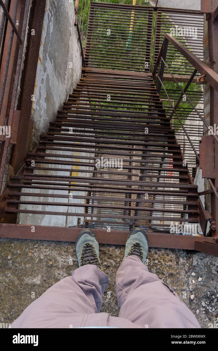Descent along the iron stairs. Human feet on the edge of the stairs ...
