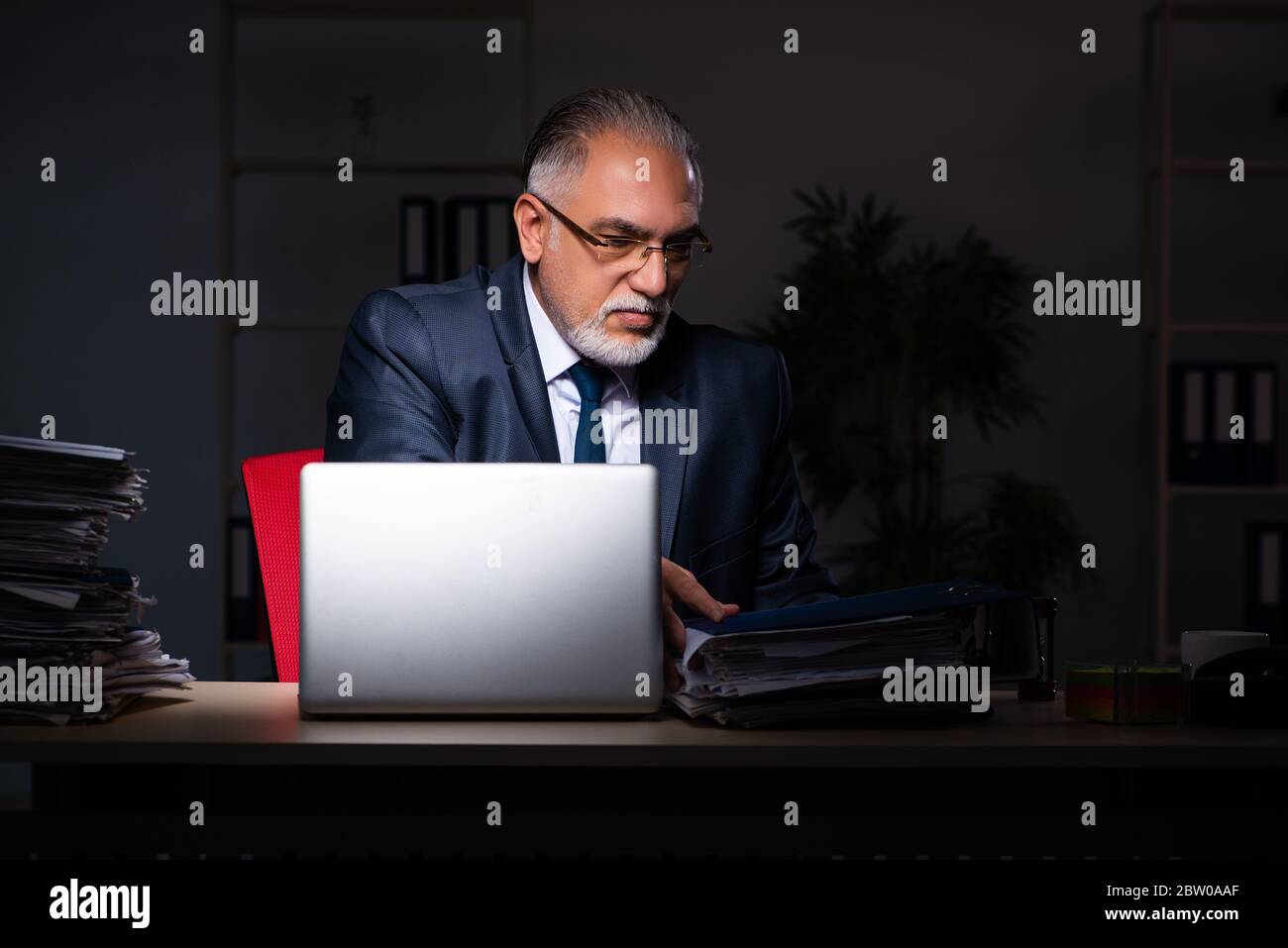 Old male employee working late at the workplace Stock Photo - Alamy