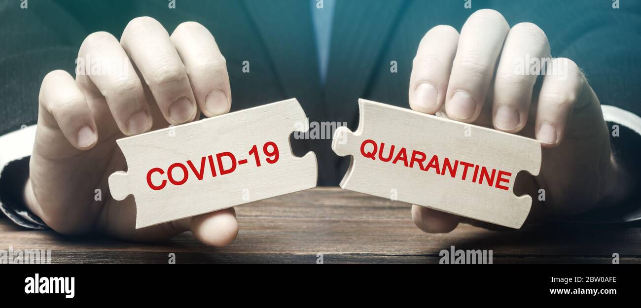 A man collects wooden puzzles with the words Covid-19 and Quarantine ...