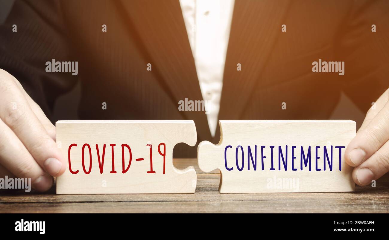 A man collects wooden puzzles with the words Covid-19 and Confinement ...
