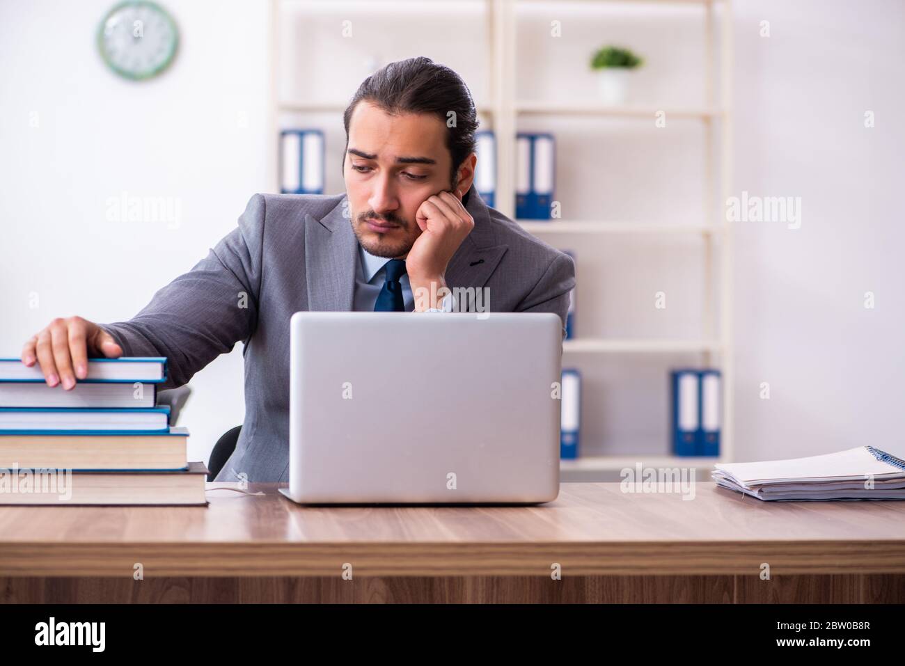 Young businessman reading books at workplace Stock Photo - Alamy
