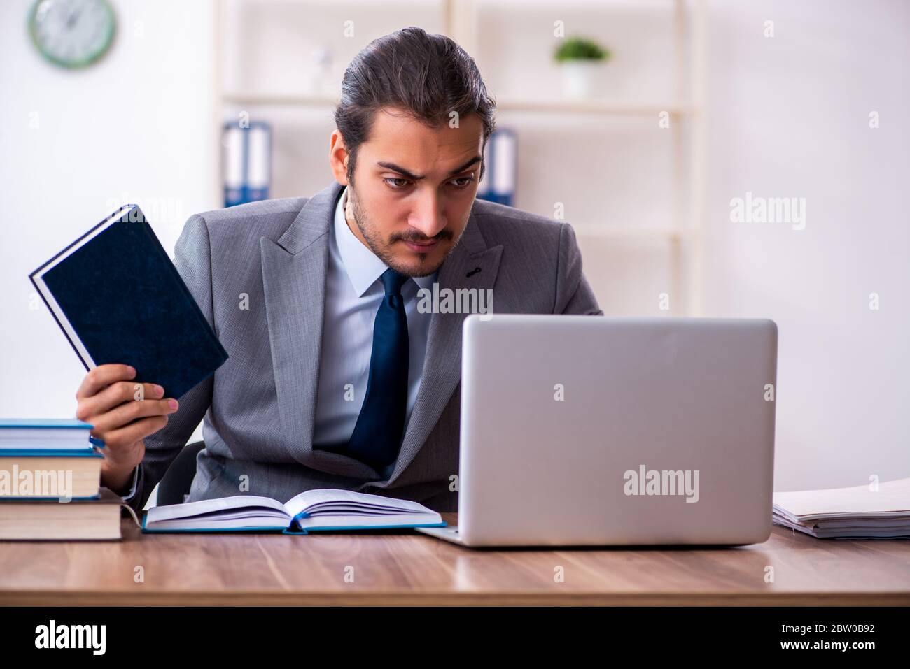 Young businessman reading books at workplace Stock Photo - Alamy