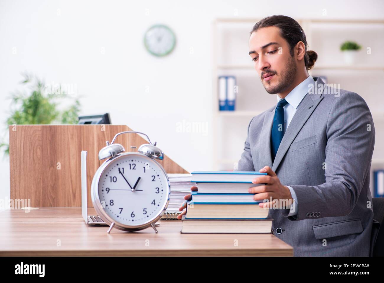 Young businessman reading books at workplace Stock Photo - Alamy