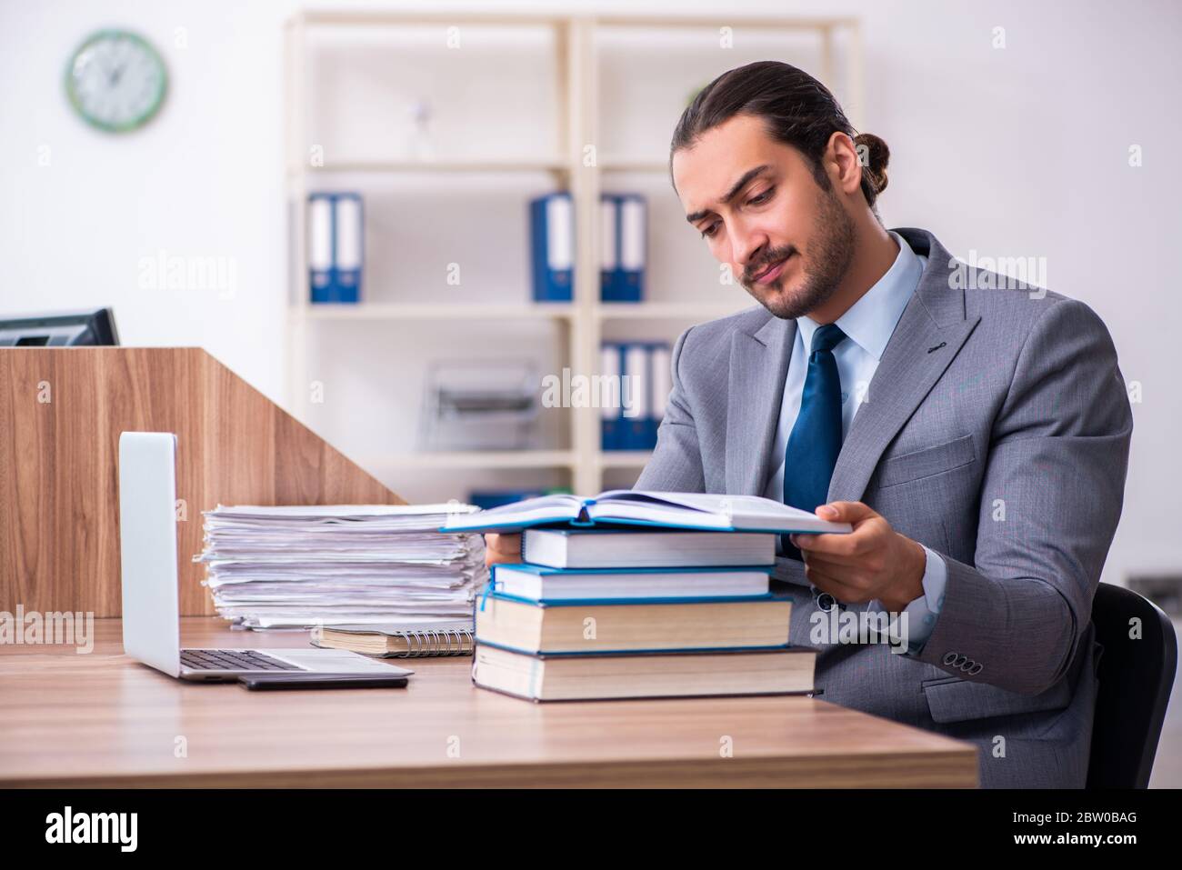 Young businessman reading books at workplace Stock Photo - Alamy