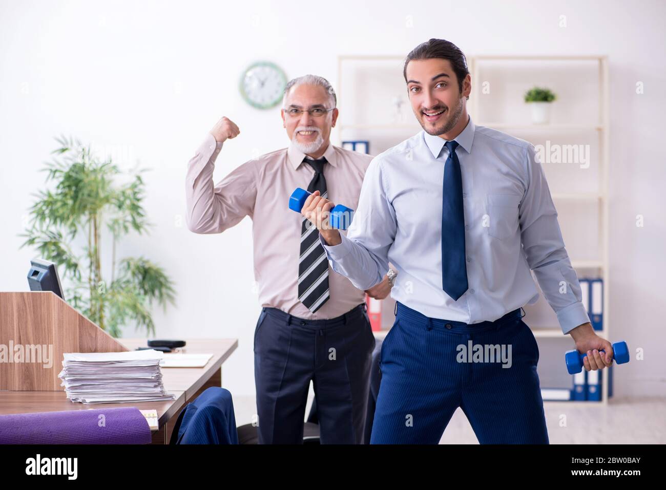 Two employees doing physical exercises at the workplace Stock Photo - Alamy