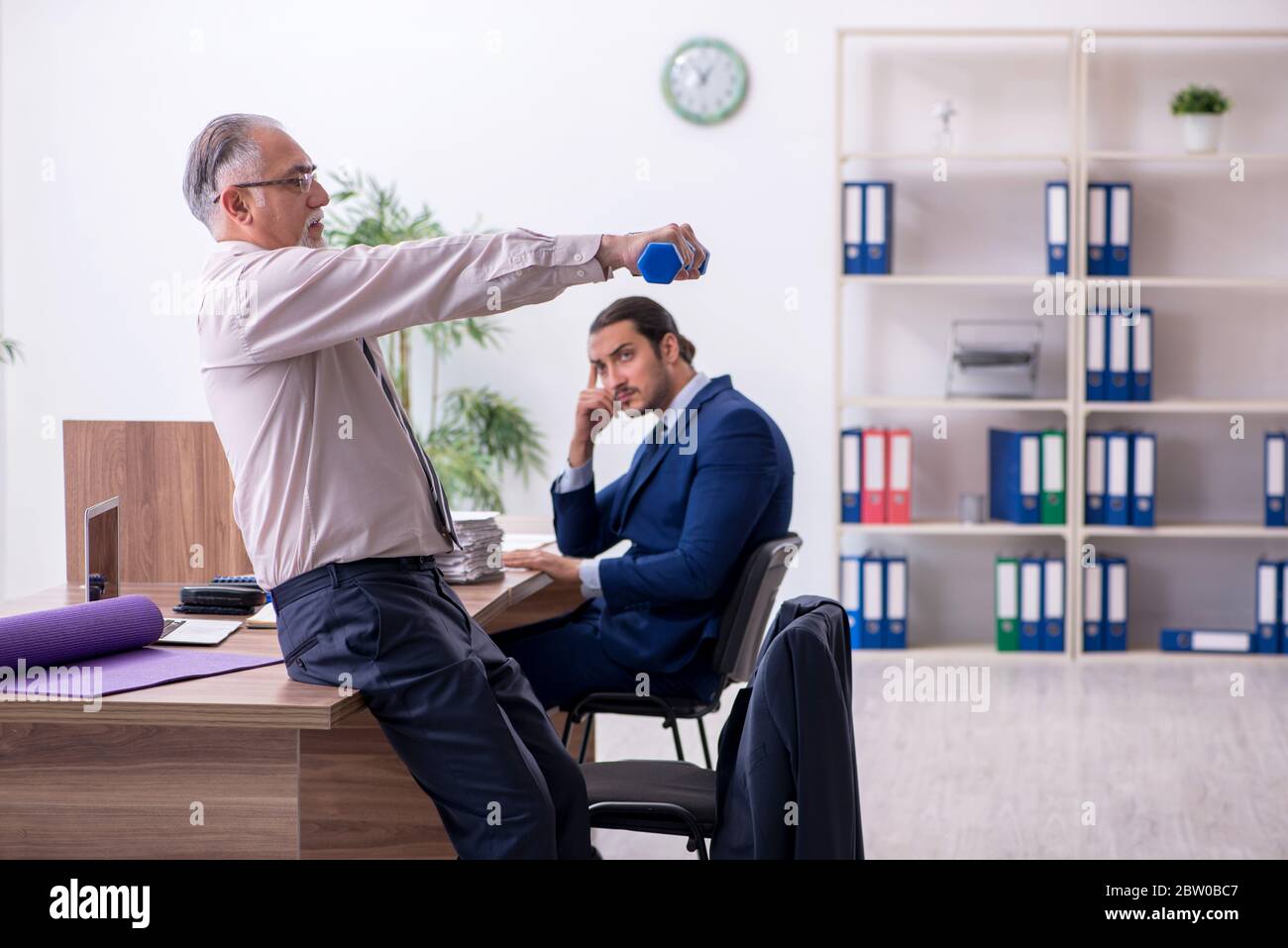 Two employees doing physical exercises at the workplace Stock Photo - Alamy