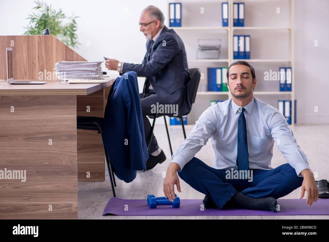 Two employees doing physical exercises at the workplace Stock Photo - Alamy