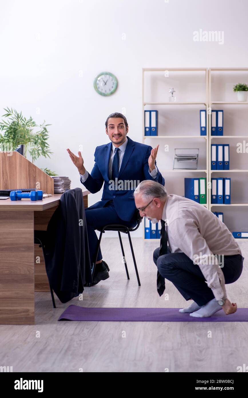 Two employees doing physical exercises at the workplace Stock Photo - Alamy