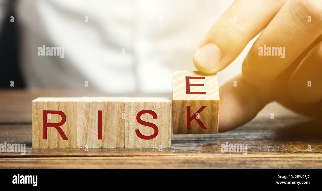 Businessman changes wooden blocks with the words Risk and Rise ...