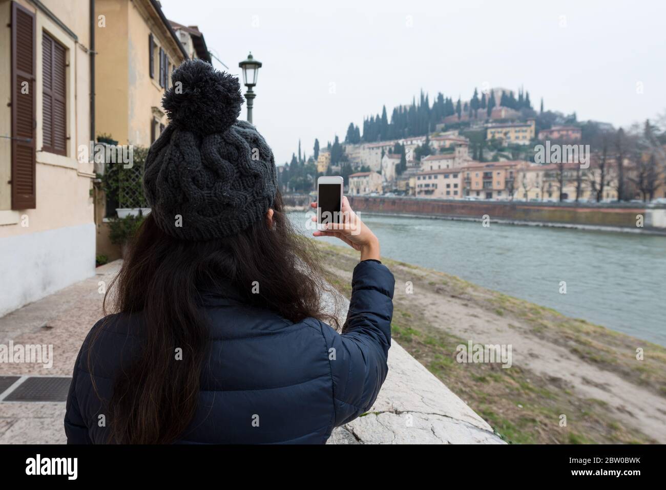Horizontal picture of brunette woman taking pictures with cellphone in ...