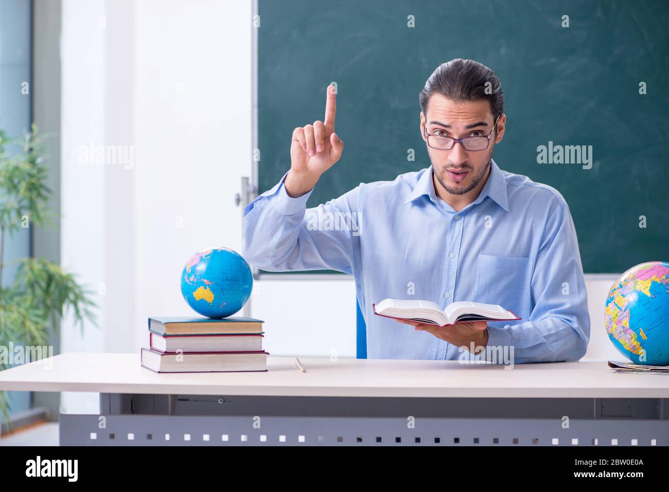 Young geography teacher in front of blackboard Stock Photo - Alamy
