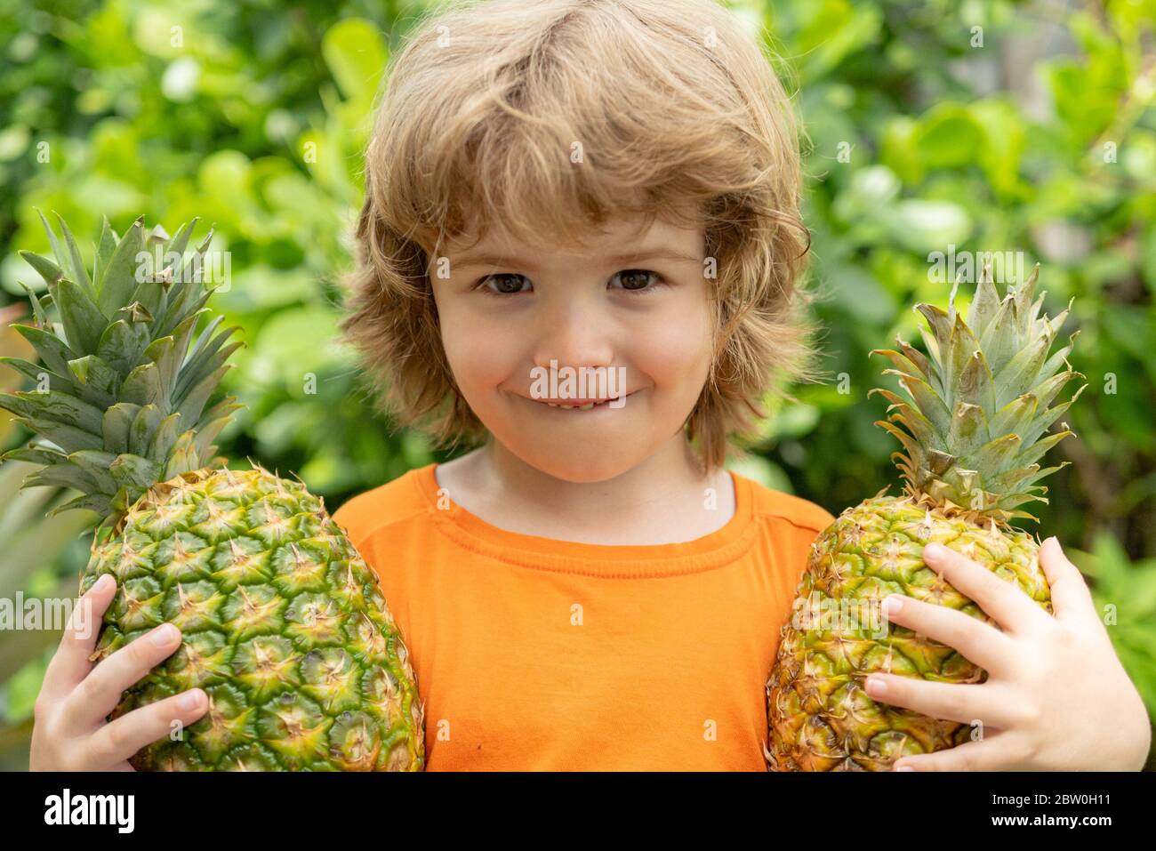 Young boy holding pineapple and smiling. Kids with pineapple Stock ...