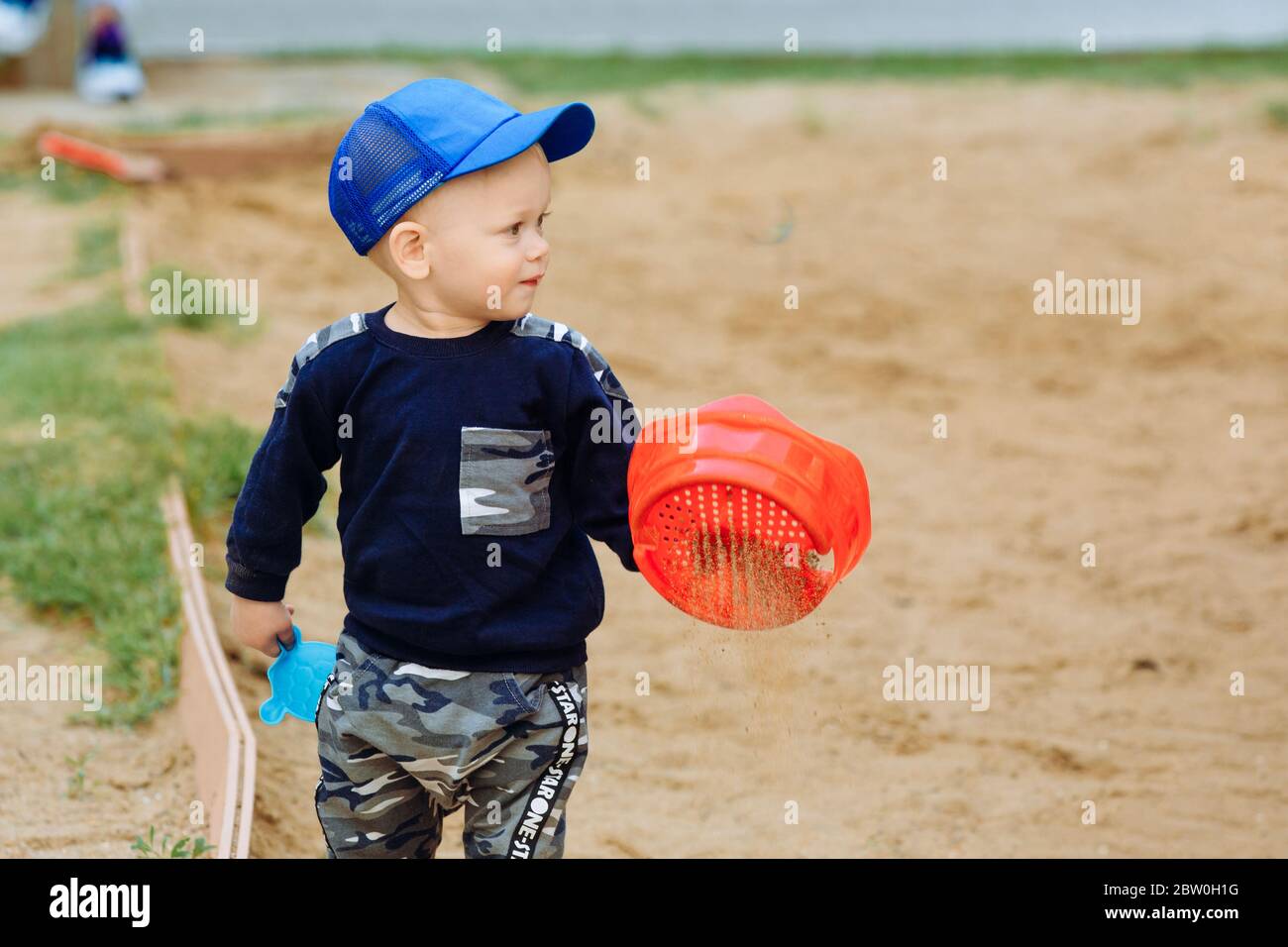 A child in a cap looks away and holds toys in his hands Stock Photo - Alamy