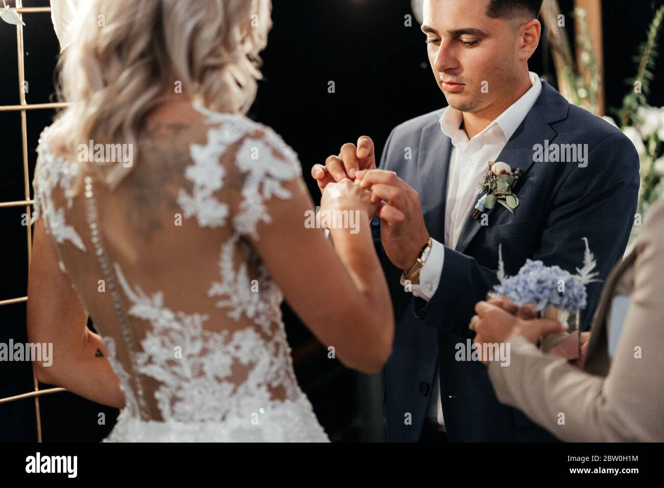 Concentrated groom putting the wedding ring on the bride's finger after ...