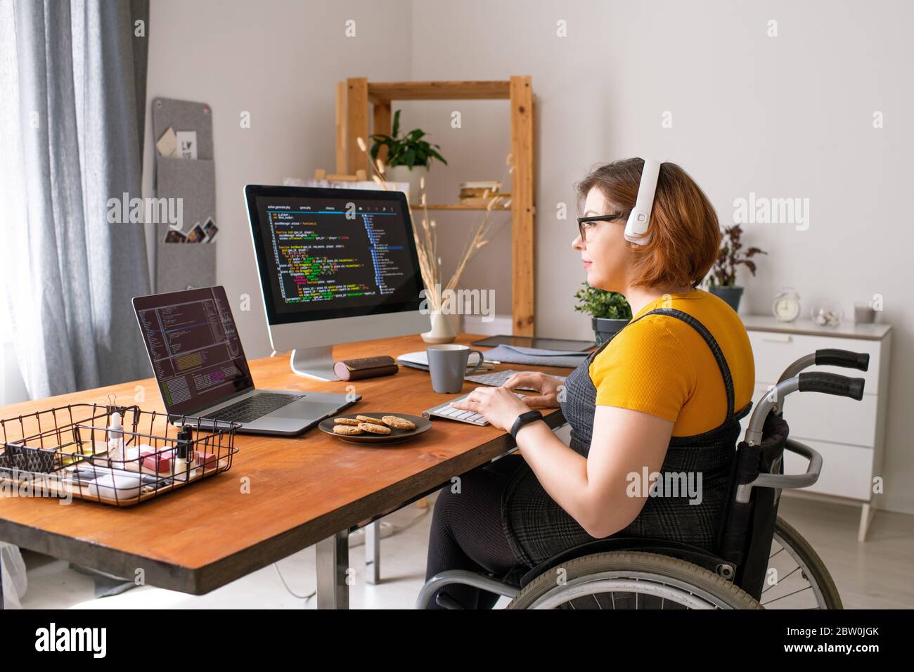 Smart disabled coder sitting in wheelchair and using computers while ...