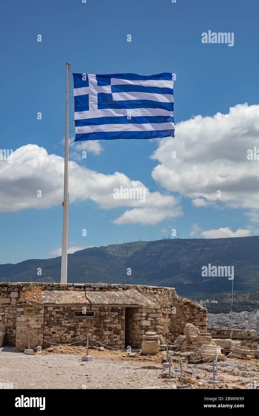 Athens Acropolis, Greece. Greek flag waving on pole, against blue sky ...
