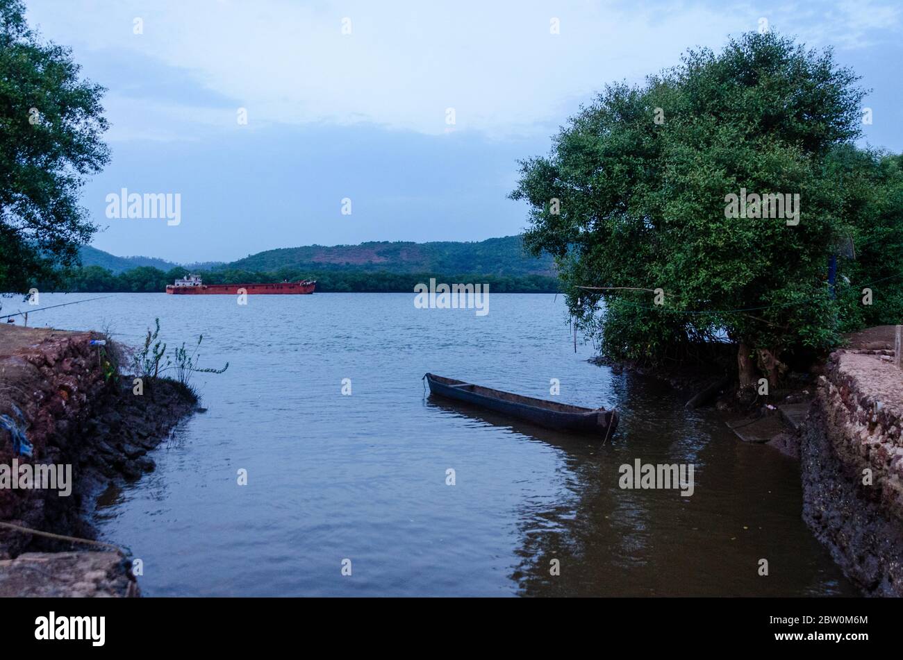 View of an empty barge making its way on Zuari River while a wooden ...