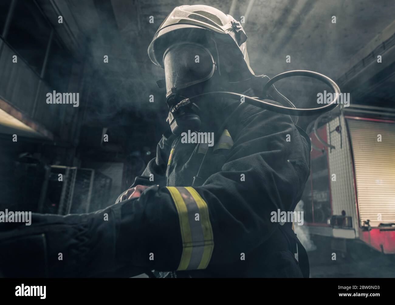 Portrait of a fireman wearing firefighter turnouts and helmet. Dark ...
