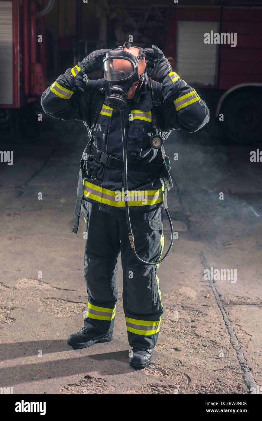 Portrait of a fireman wearing firefighter turnouts and helmet. Dark ...