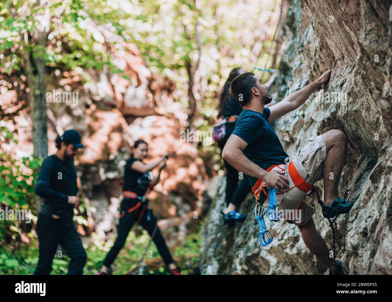 Young team of climbers climbs on a rocky wall in a valley with ...