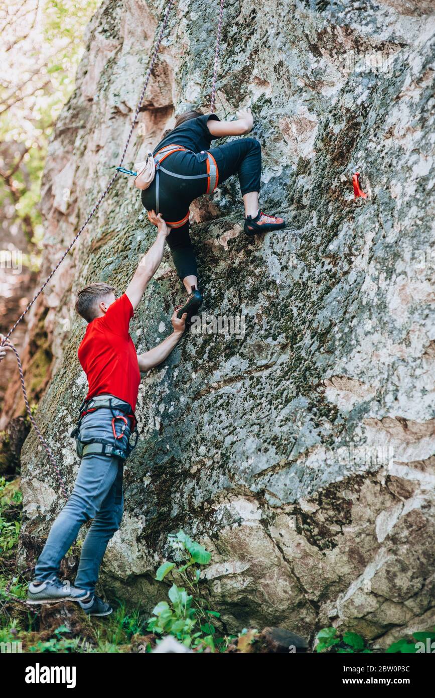 Climbing in nature. Friends train on natural terrain. A partner insures ...