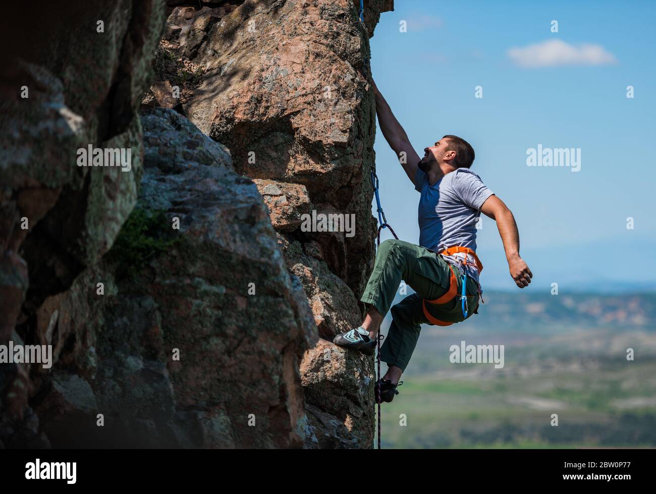 Muscular rock climber practicing rock-climbing on a rock wall Stock ...